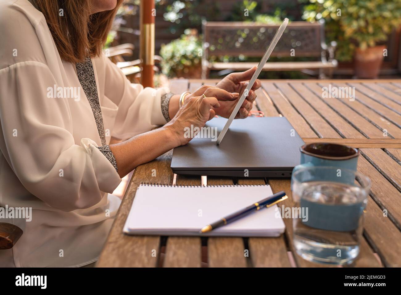 Woman teleworking from the garden of her house with a tablet Stock ...