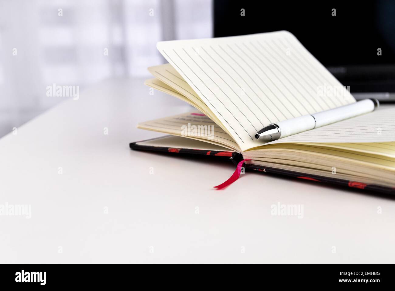 White office desk with open notebook, pen, laptop and other office ...