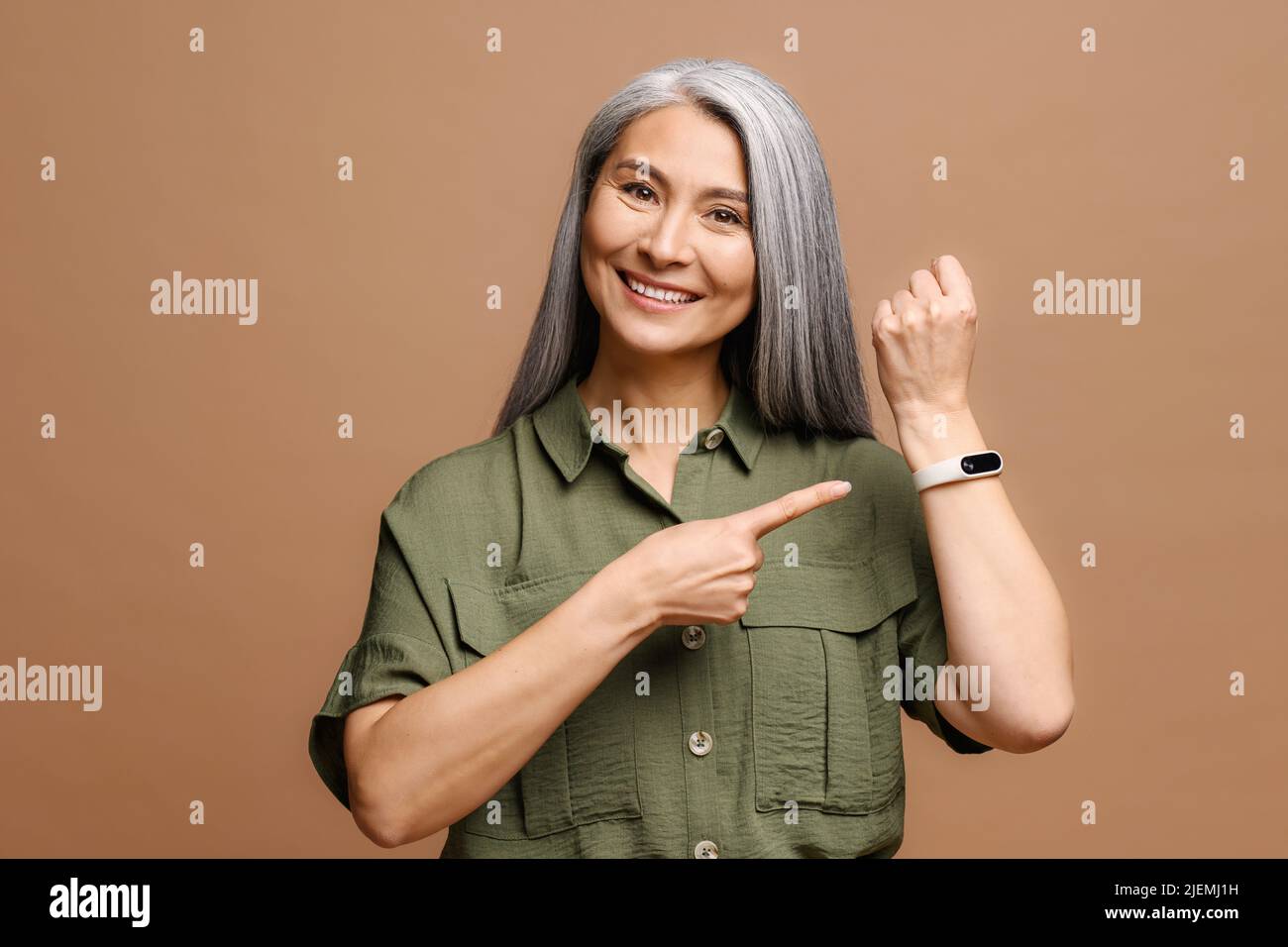 Happy positive woman with grey hair in pointing finger on watch on her ...