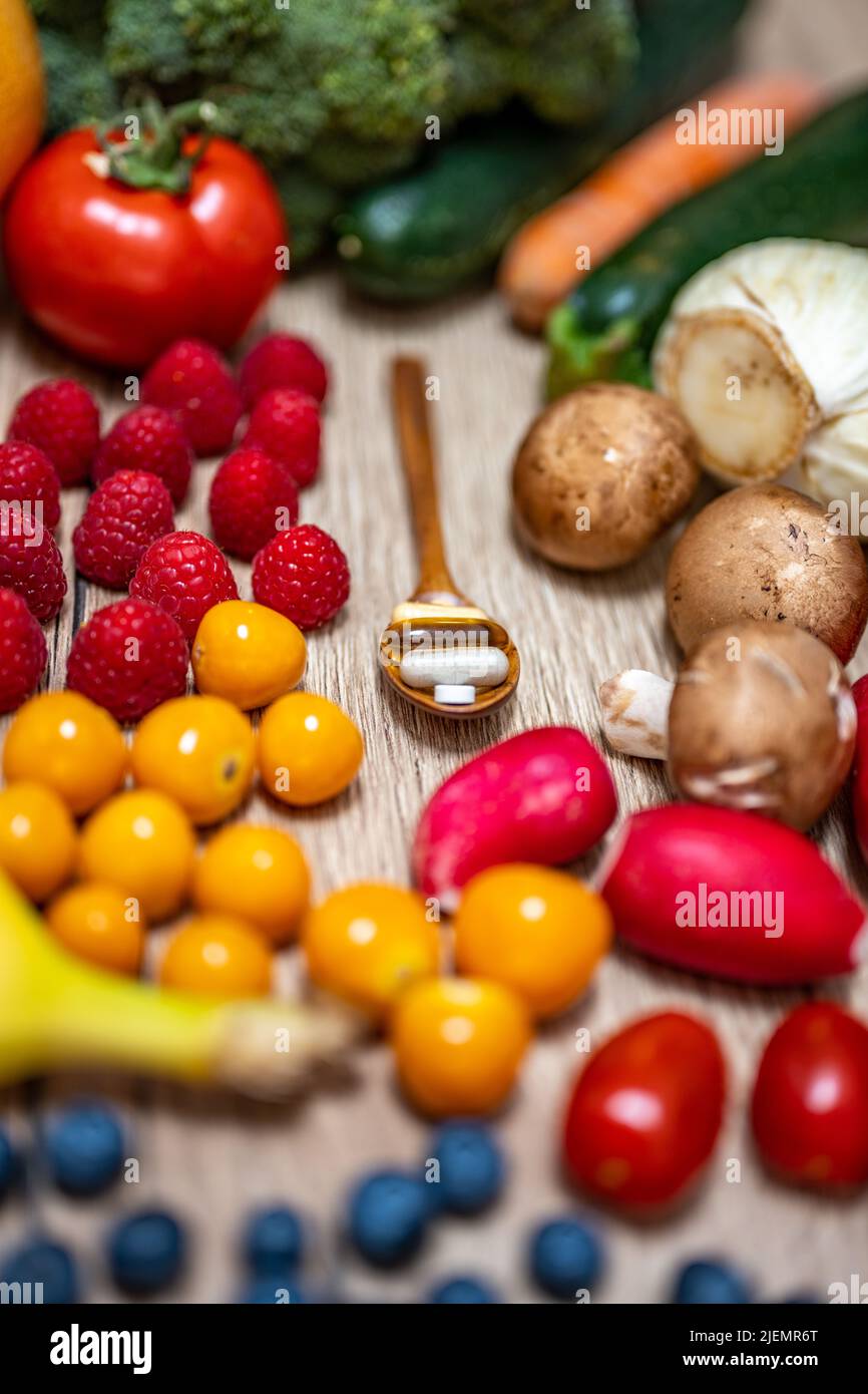 A wooden spoon with food supplements is placed in the middel of fresh ...