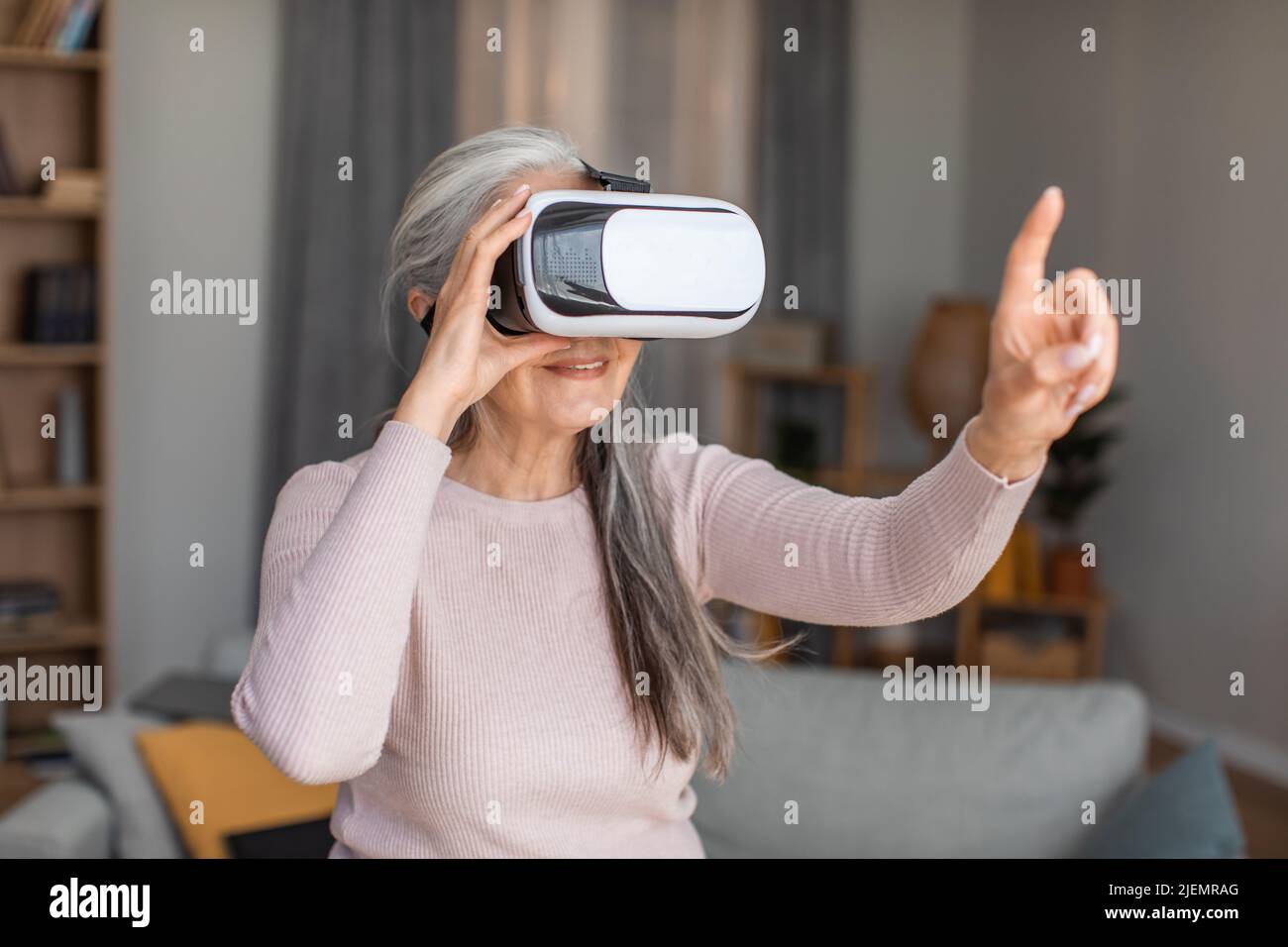 Cheerful european senior woman with gray hair in vr glasses plays in ...