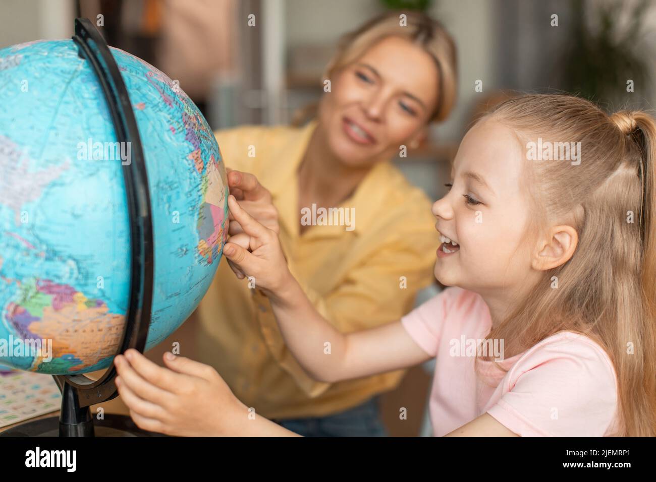 Cheerful female tutor teaching child geography, girl learning about the ...