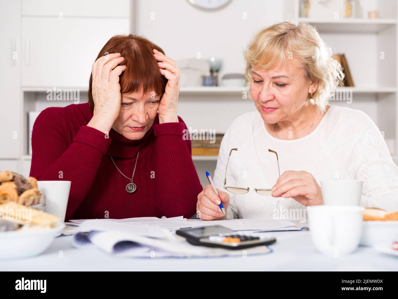 Worried mature female friends with papers Stock Photo - Alamy