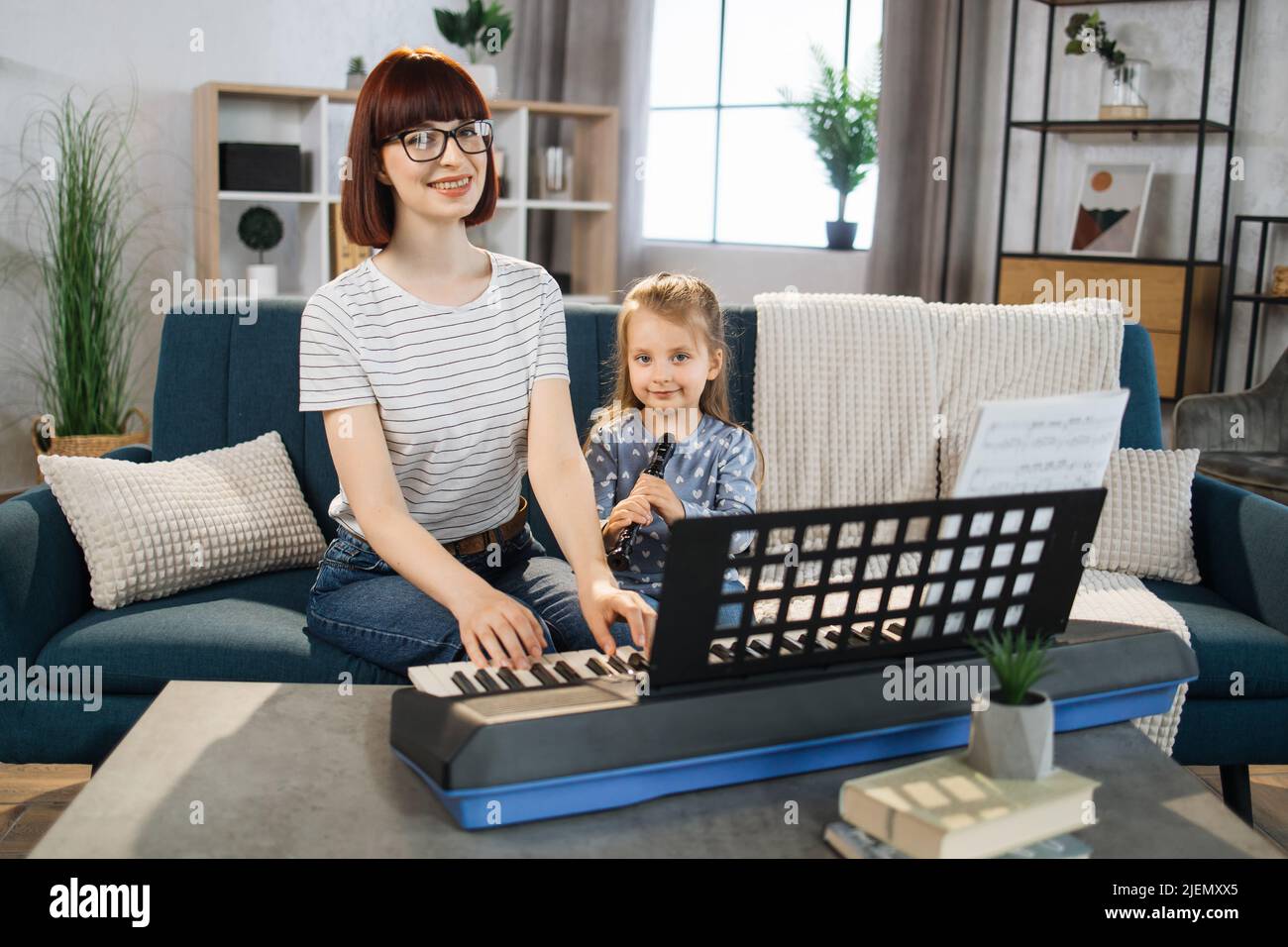Little cute girl with music teacher having lesson at flute at school of ...