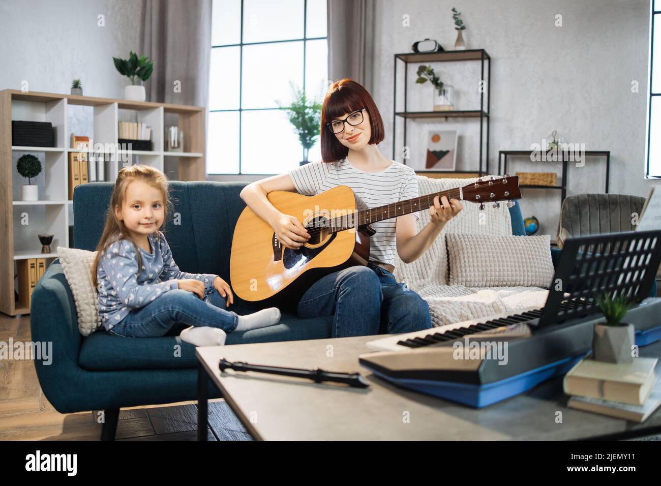 Little cute girl with music teacher having lesson at guitar at school ...