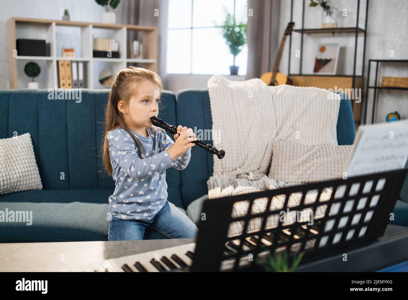 Beautiful young charming little girl smiling while playing classic ...
