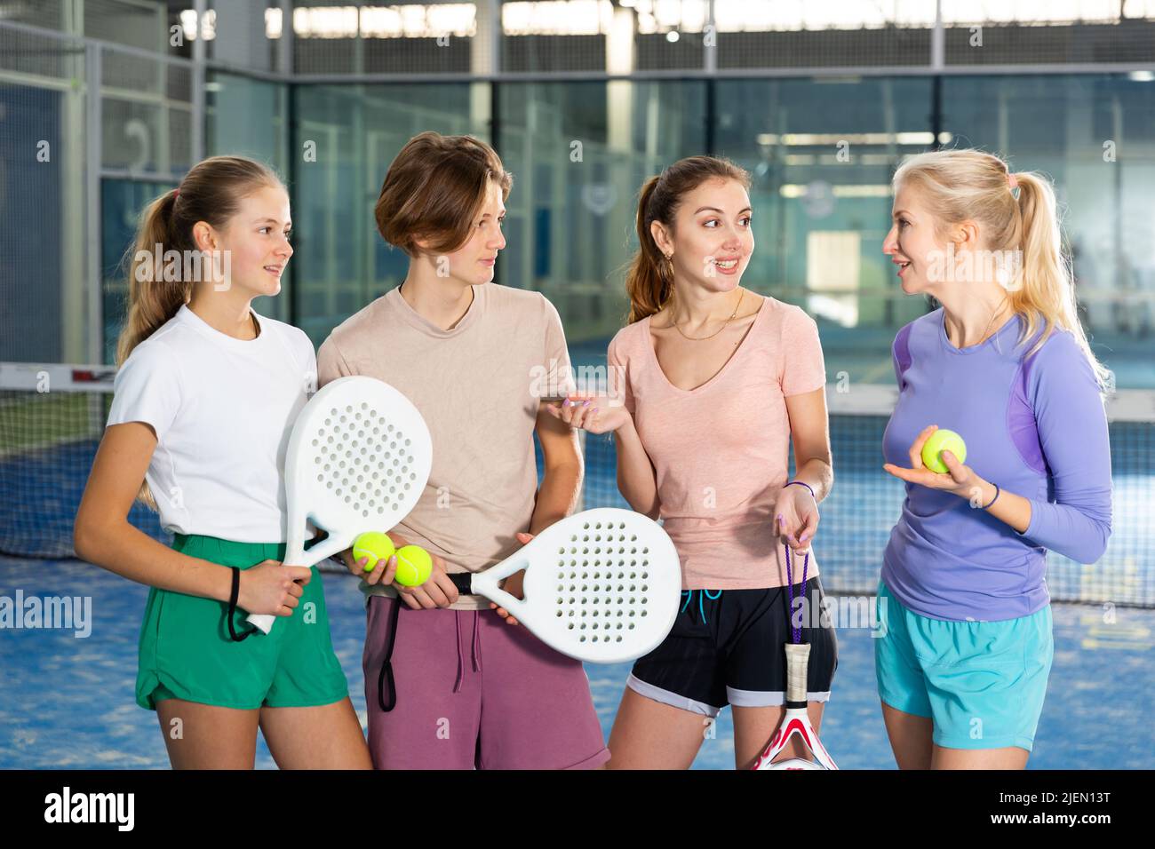 Four padel players standing in court and having conversation Stock ...