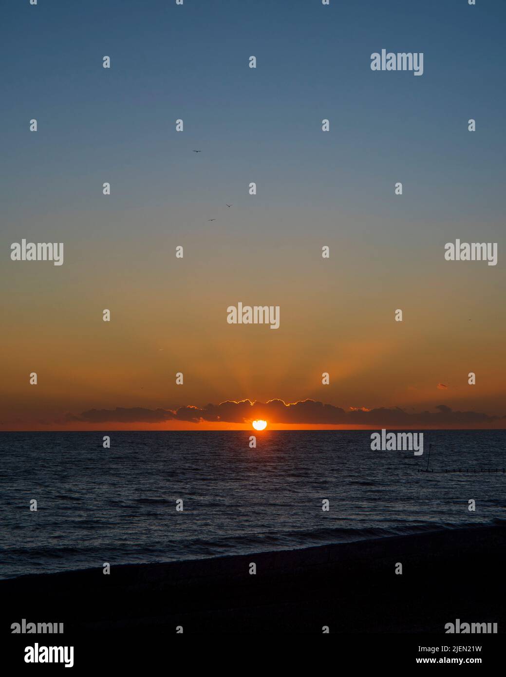 Sunsetting over the sea in Brighton, UK. Sunrays visible as the sun ...