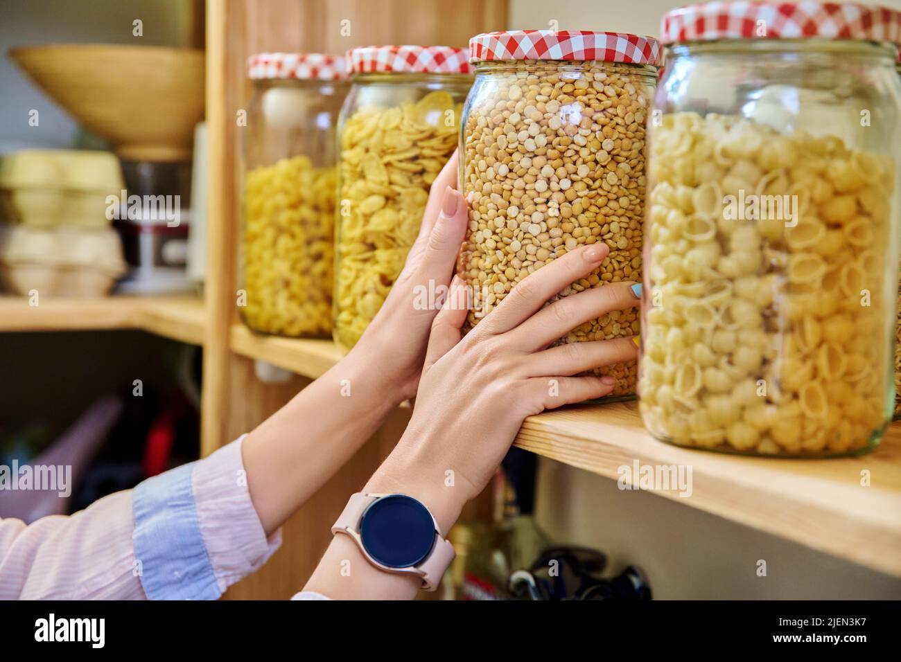 Storage of food in the kitchen in pantry, woman's hands with can of dry ...