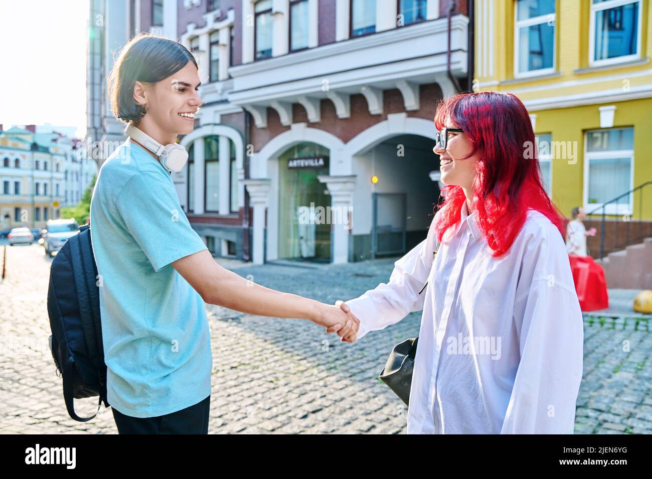 Meeting, shaking hands teenage male and female friends on the city ...