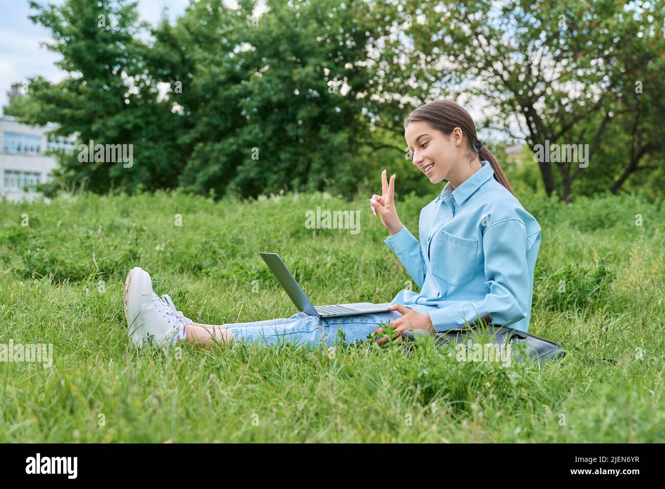 Teenage girl high school student using laptop while sitting on green ...
