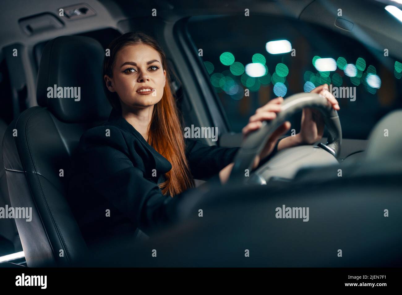 horizontal photo of a cute, relaxed woman sitting behind the wheel of a ...