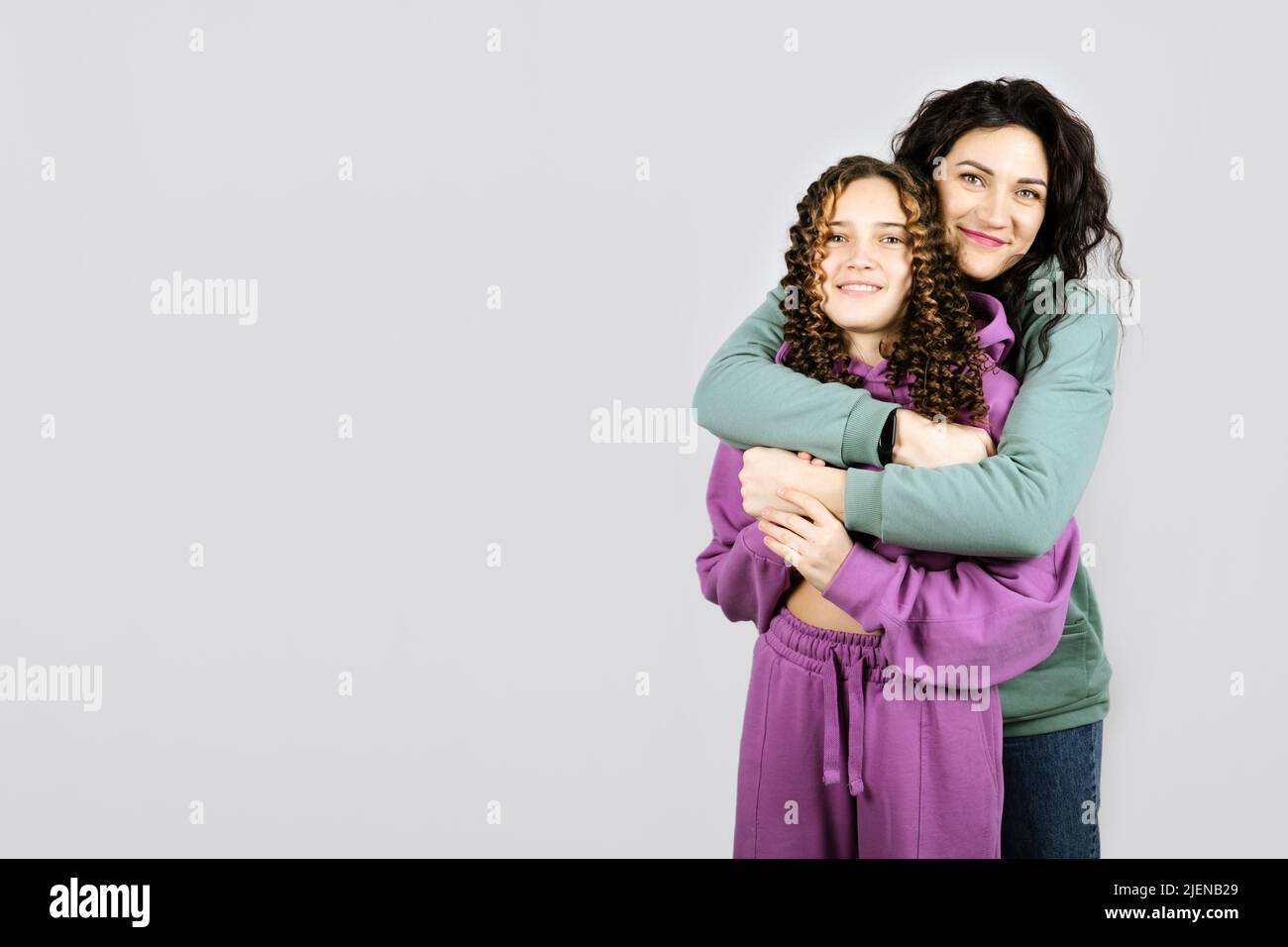 Portrait of happy mom and teen daughter spend time together. Teenage girl hugging her mother and ...