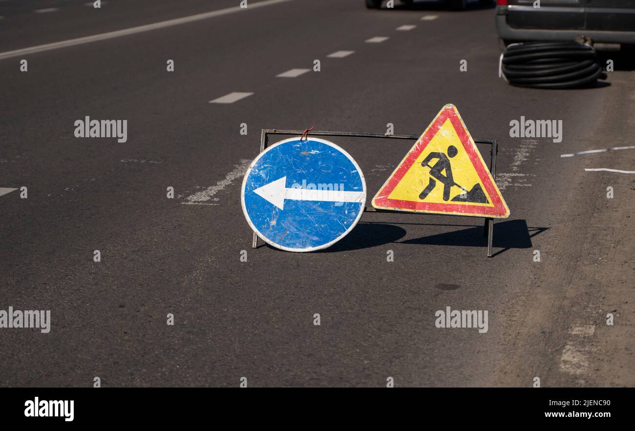 Road works sign on the road. Repair of road signs and a bypass arrow ...