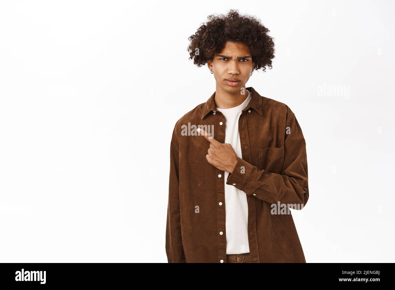 Portrait of confused young man pointing finger left, looking concerned ...