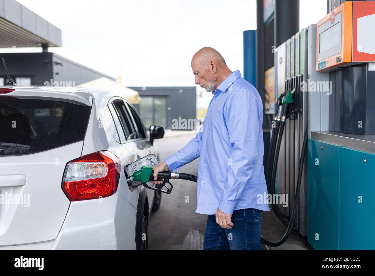 Senior businessman standing on gas station and fueling car Stock Photo ...