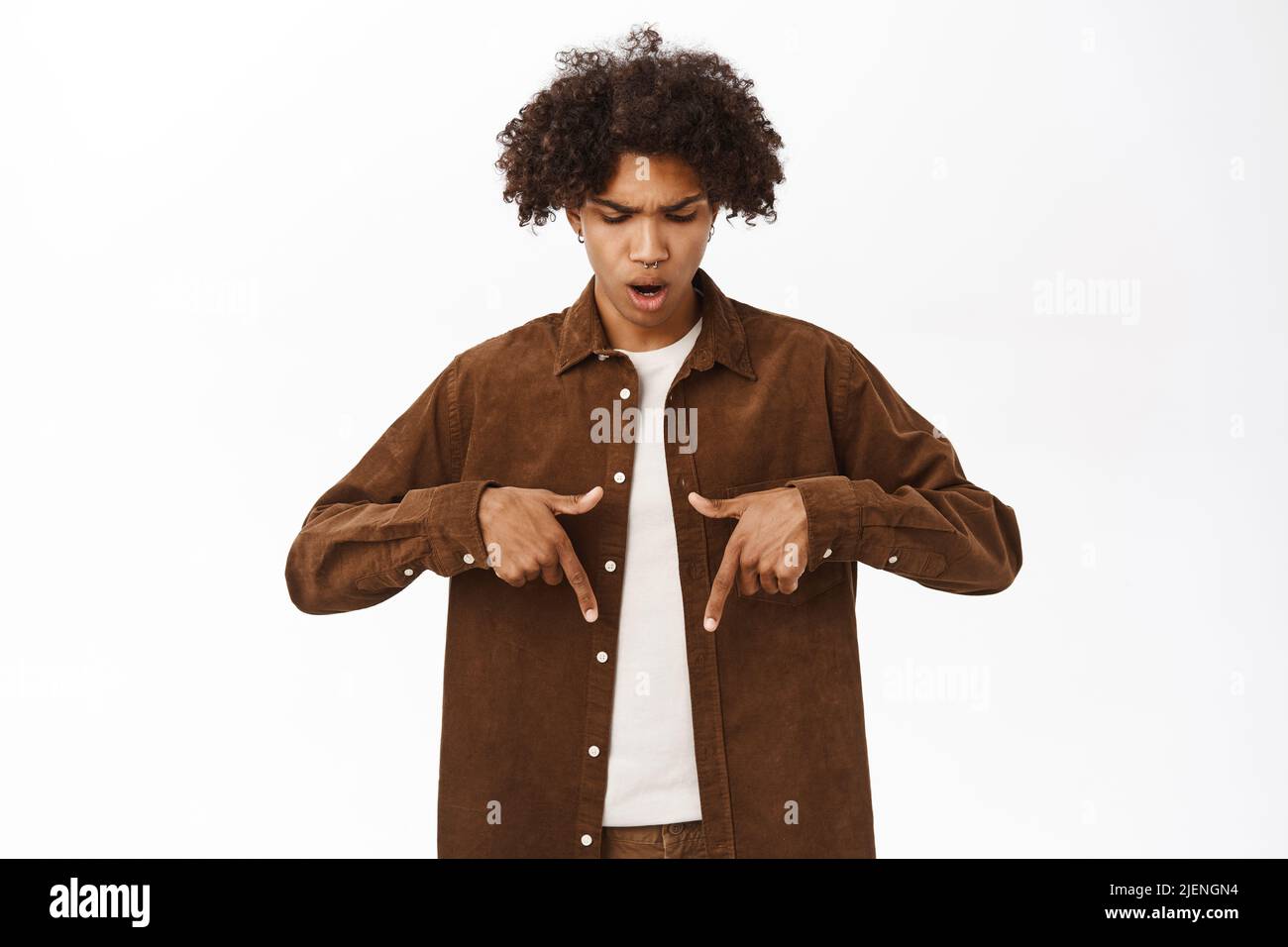 Shocked boy pointing and looking down with startled face, seeing smth ...