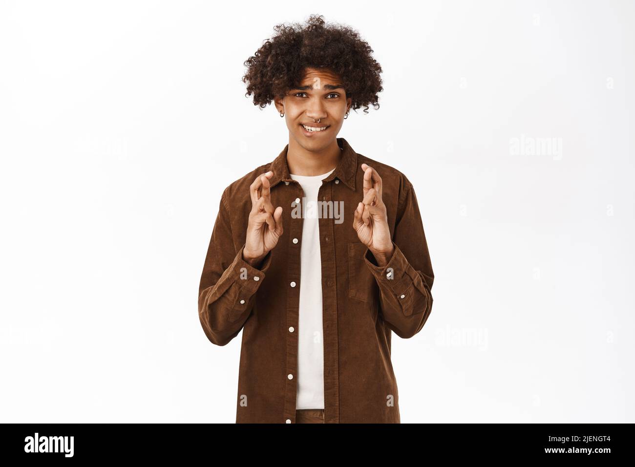 Hopeful smiling young man wishing, holds fingers crossed and ...