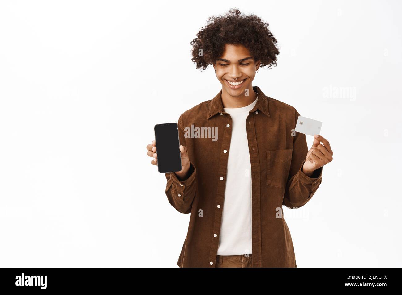 Portrait of smiling young male model shows mobile phone screen, app ...