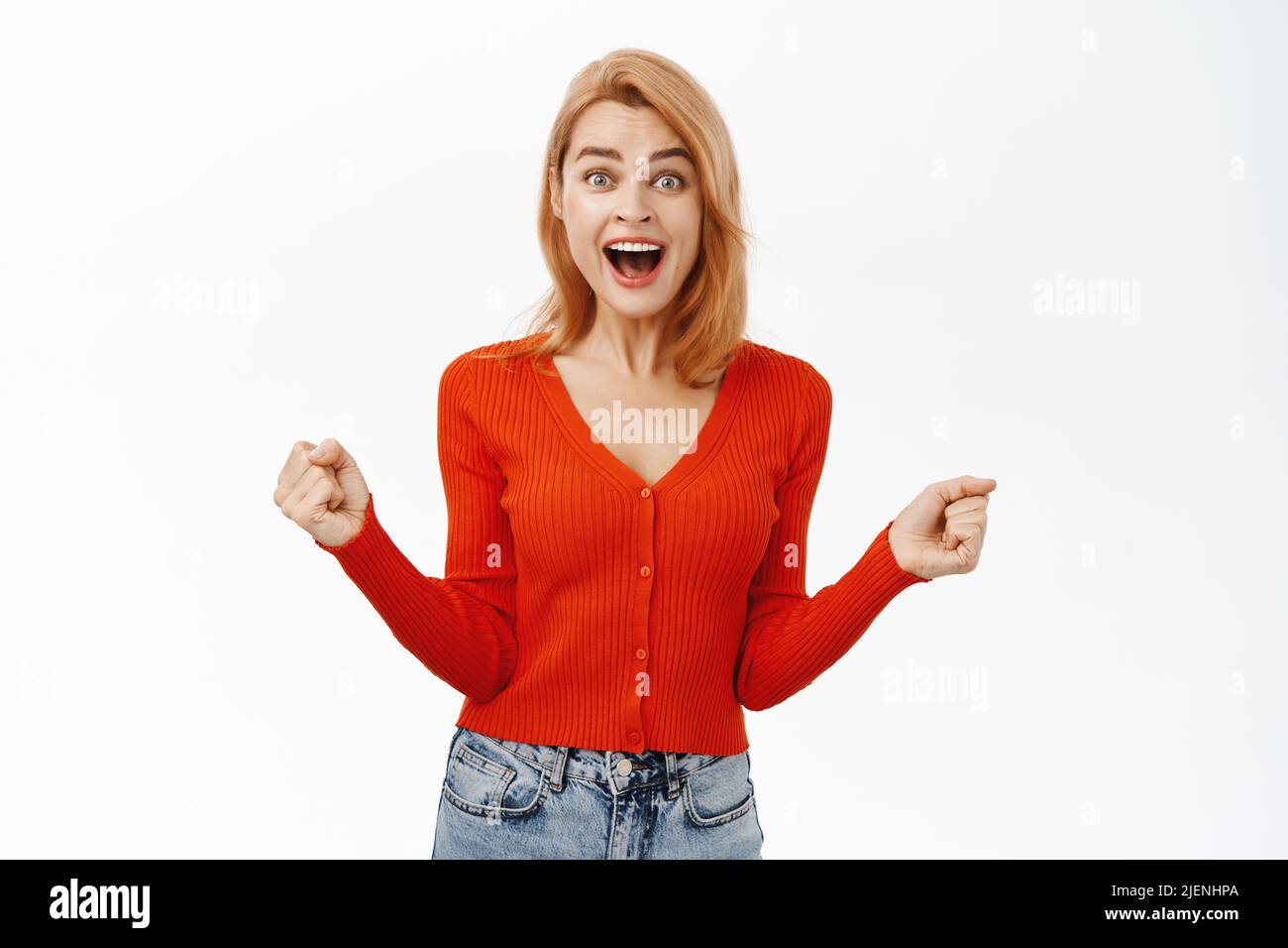 Young woman triumphing, scream from excitement, looks surprised, stands ...