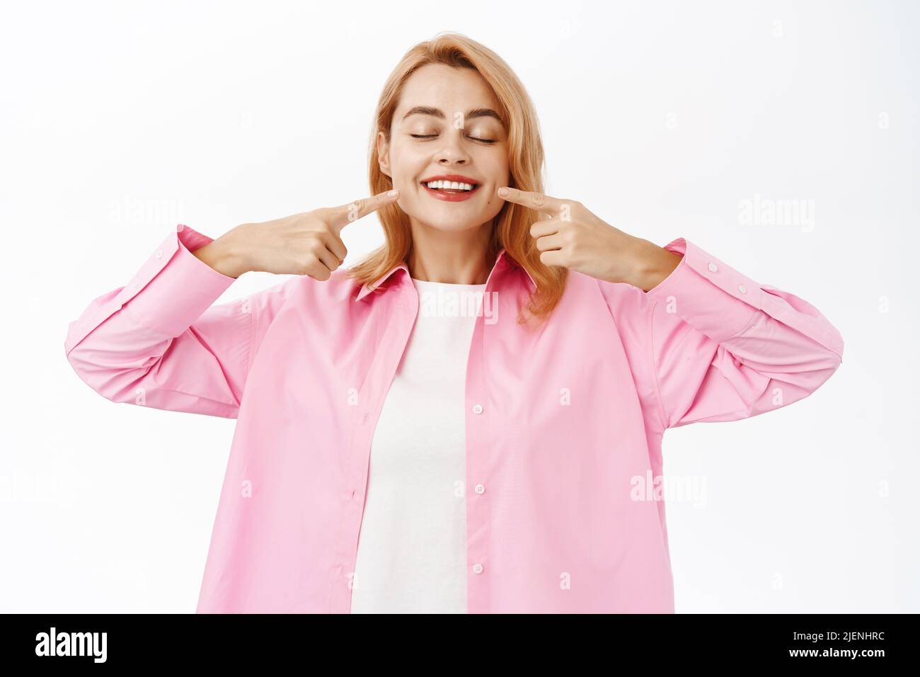 Perfect white smile. Happy young woman smiling, pointing at her healthy ...