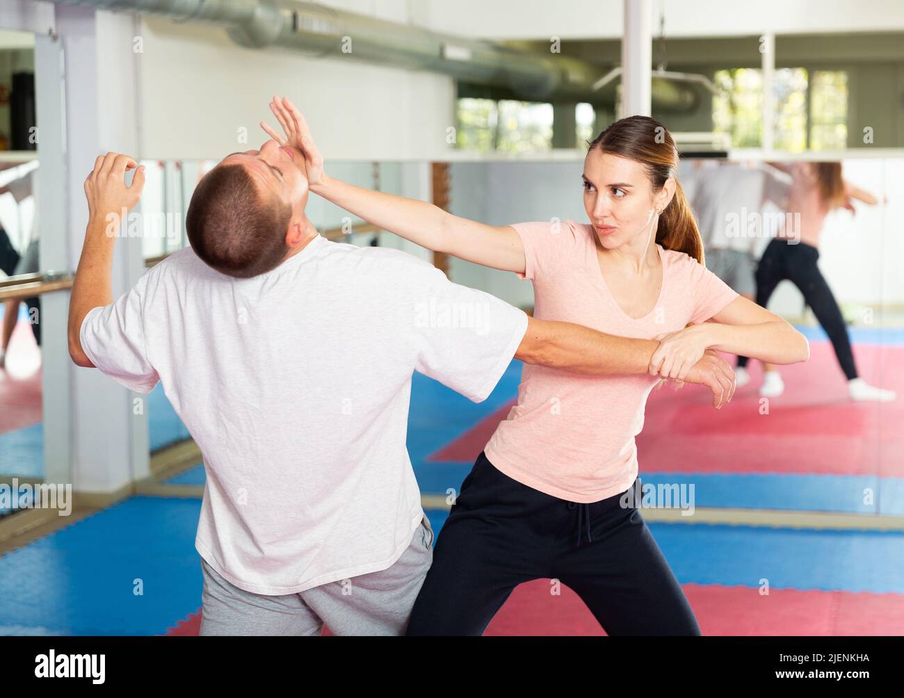 Young woman practicing palm strike with man in self defense training ...