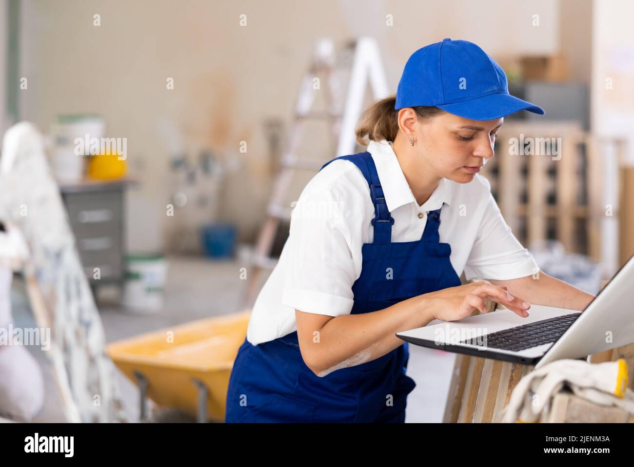 Portrait of a female builder who checks the work done using laptop ...