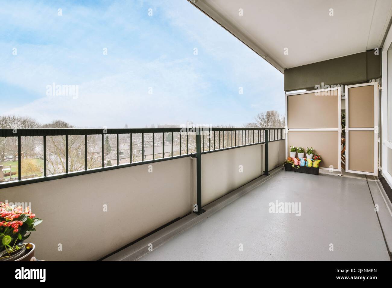 SpaciSpacious white balcony with black metal railings, flower pots and ...