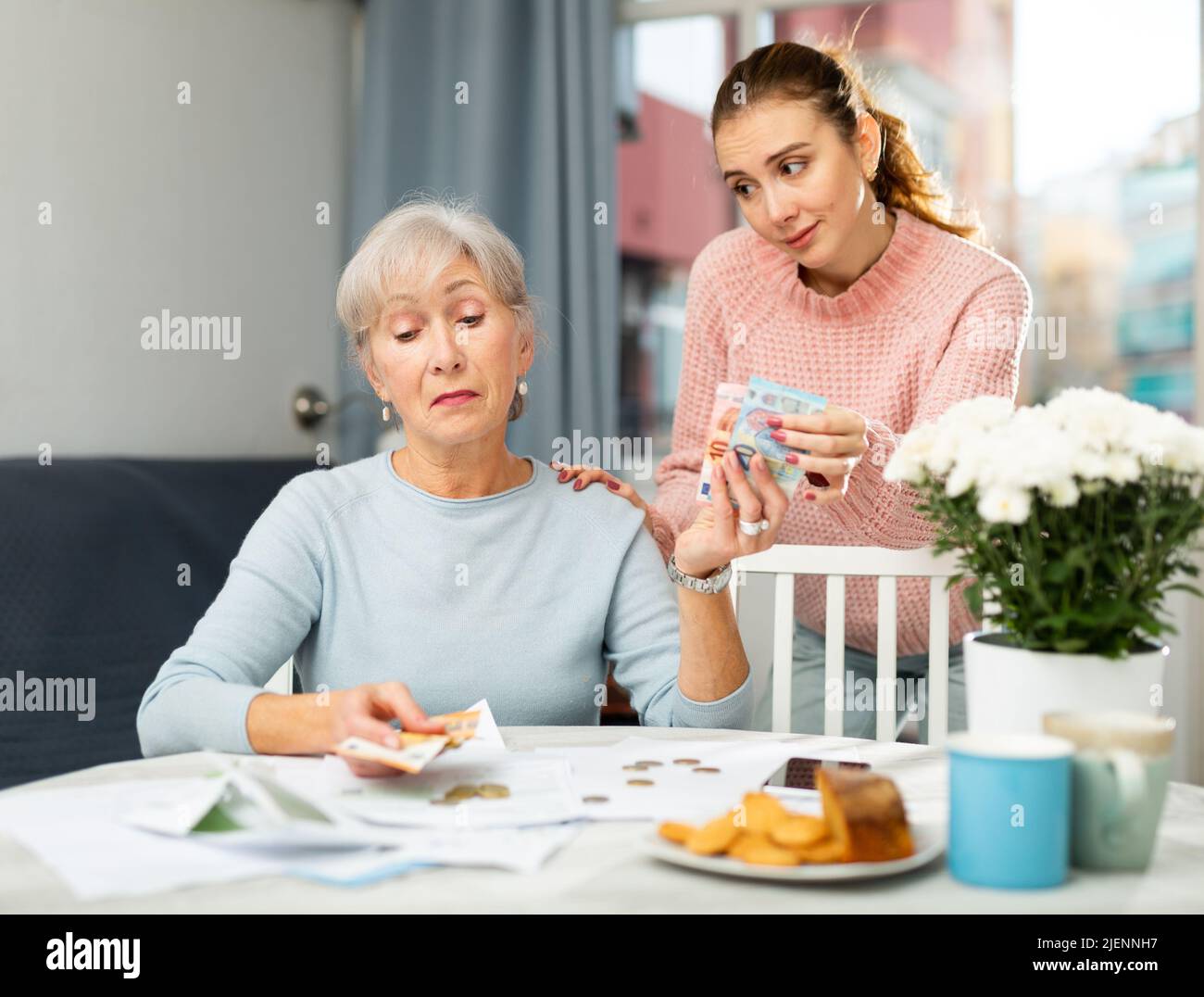 Young woman receiving money from her senior mother Stock Photo - Alamy