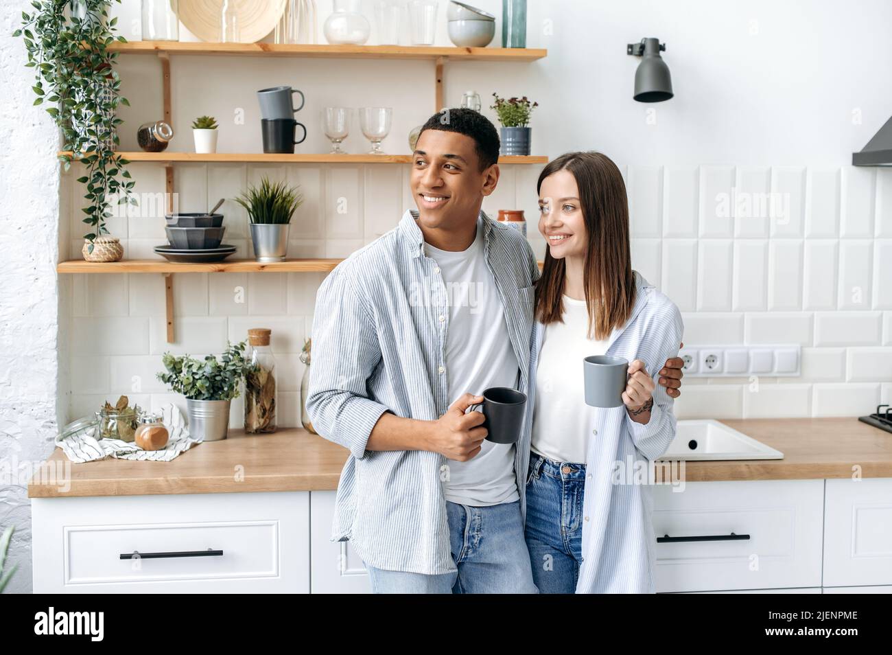 Happy multiracial romantic couple, newlyweds, stylishly dressed, stand ...