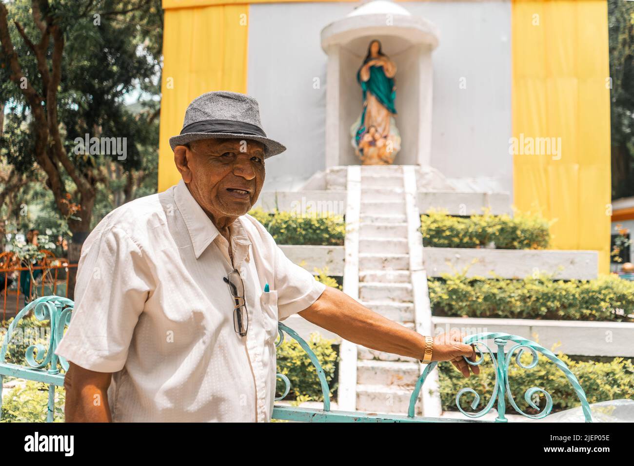 Religious older man visiting a statue of the virgin mary in the central ...