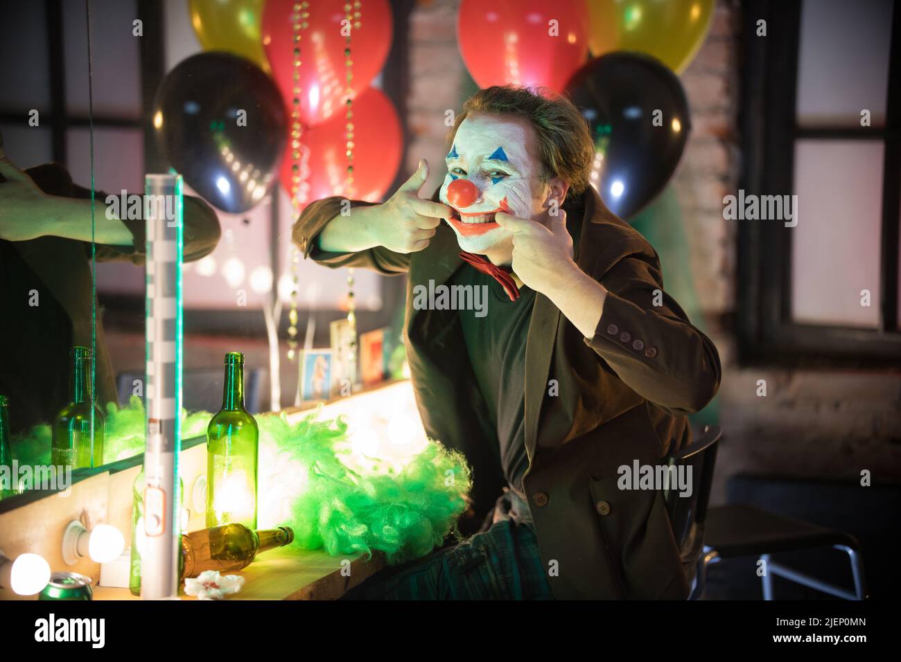 Clown in the dressing room concept - a crazy man clown looking in the ...