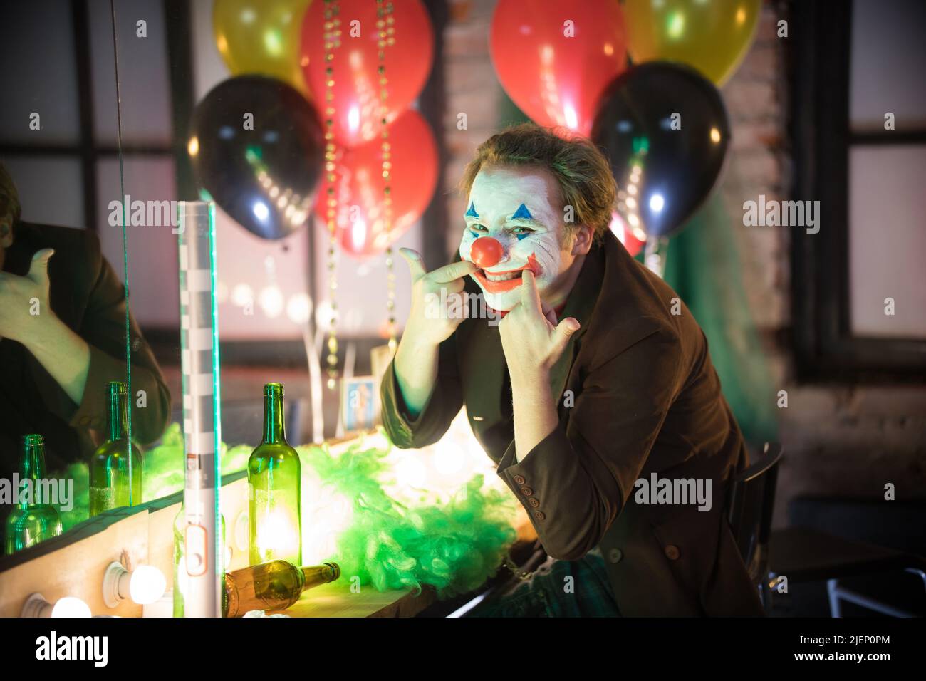 Clown in the dressing room concept - a crazy man clown looking in the ...