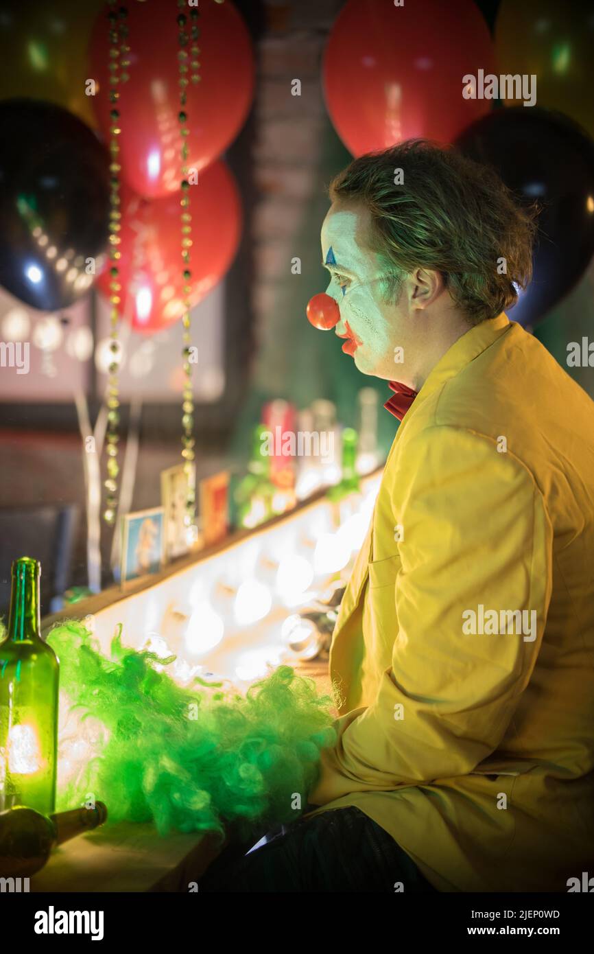 Clown concept - a bored man clown in yellow jacket sitting in the ...