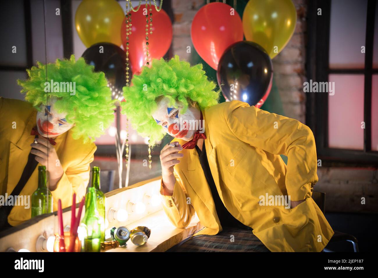 Clown concept - a sad tired man clown in yellow jacket and green wig ...