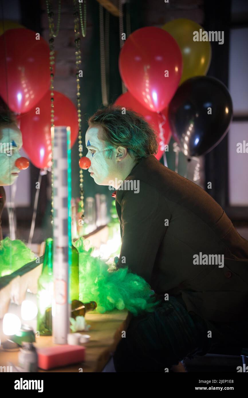 Clown concept - a man sitting in the dressing room with a paint and ...