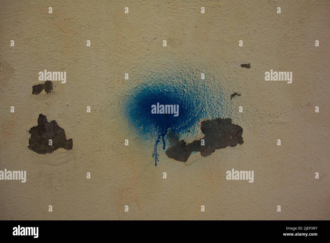 blue aerosol splodge with background peeling white paint with textured ...
