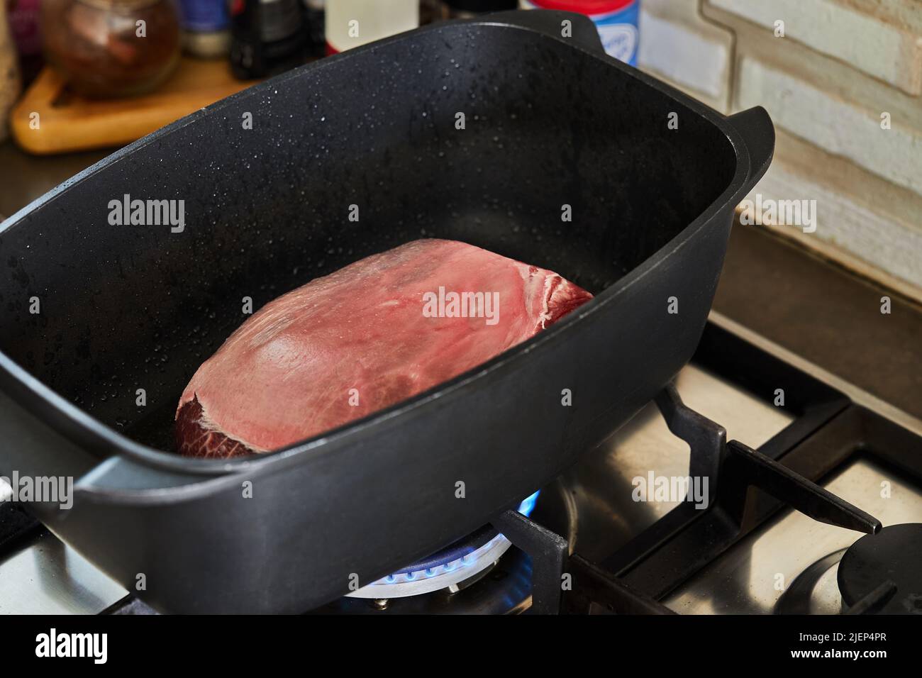 Piece of meat is roasted in rectangular pot for cooking over fire on ...