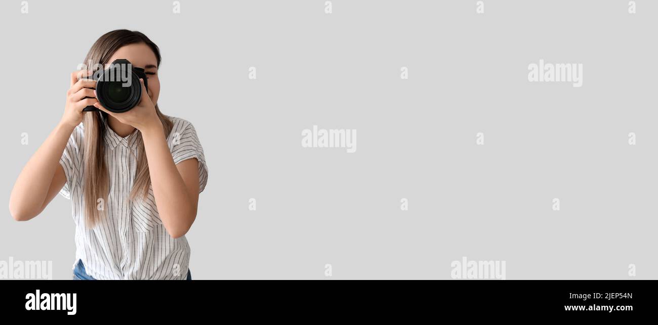 Female photographer with modern camera on light background with space ...