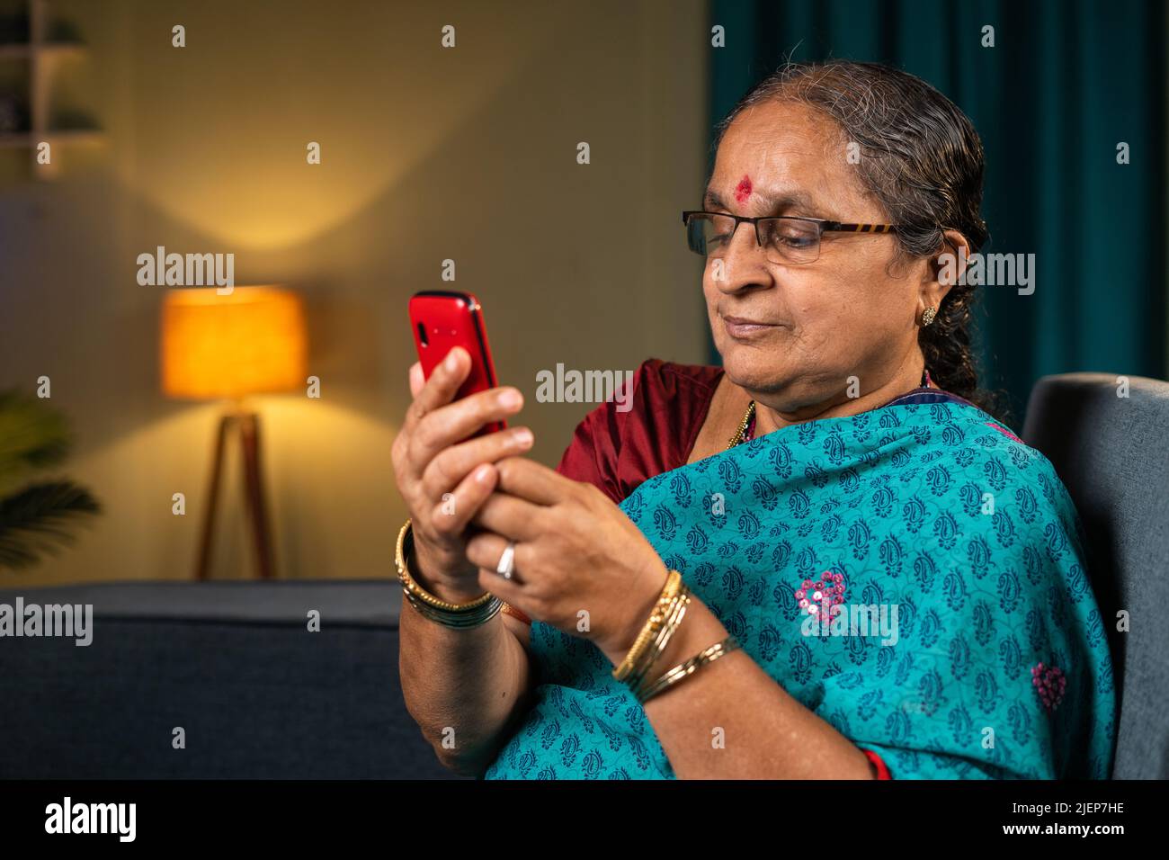 Old women using basic keypad mobile phone while at home - concept of ...