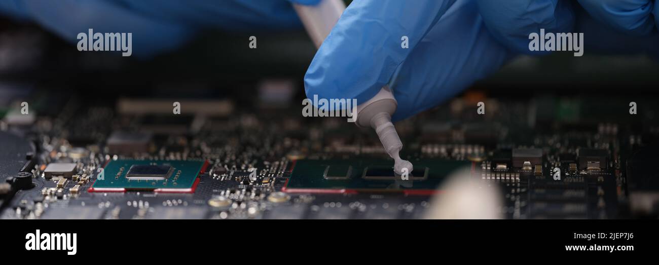Gloved hands hold thermal paste on a laptop chip Stock Photo - Alamy