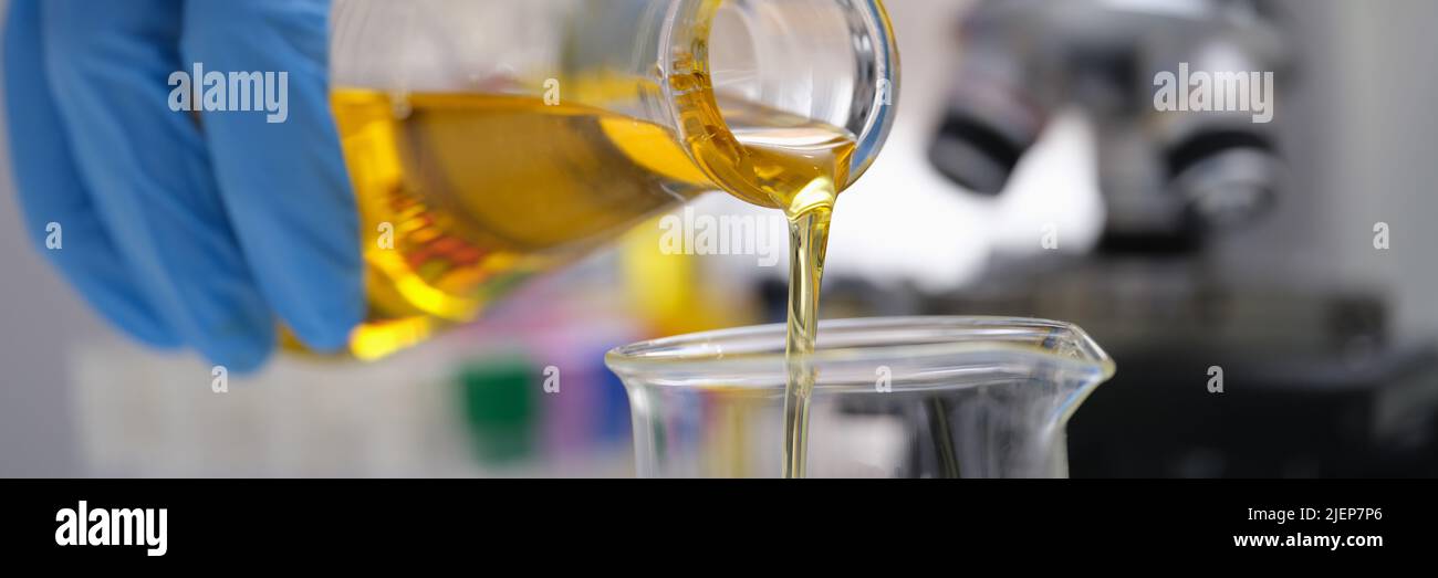 A hand in a glove pours a yellow liquid in the laboratory Stock Photo ...