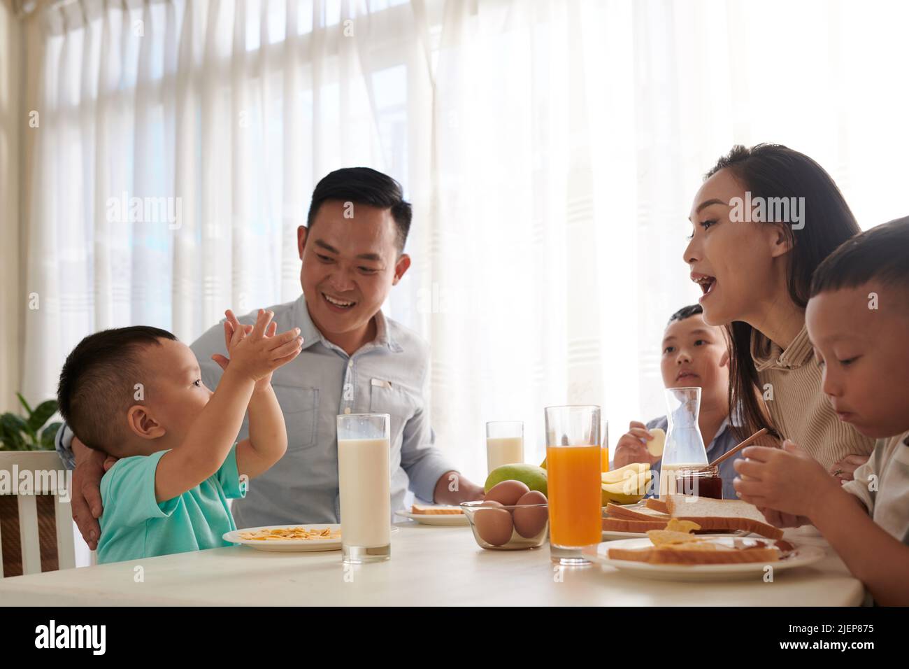 Little boy telling story to his family during breakfast Stock Photo - Alamy
