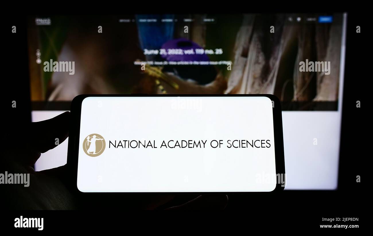 Person holding mobile phone with logo of National Academy of Sciences ...
