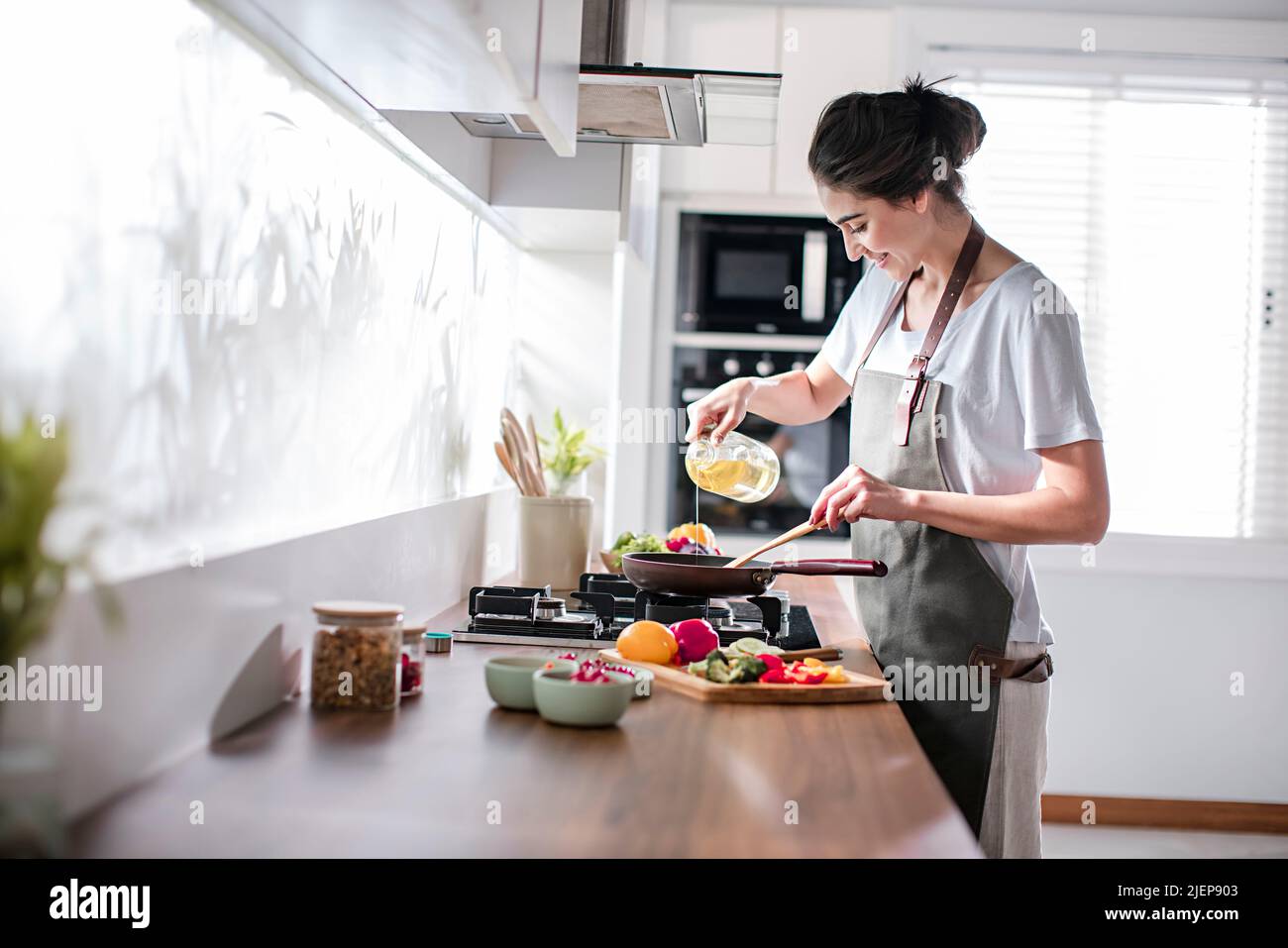 Young woman pouring oil in hi-res stock photography and images - Alamy