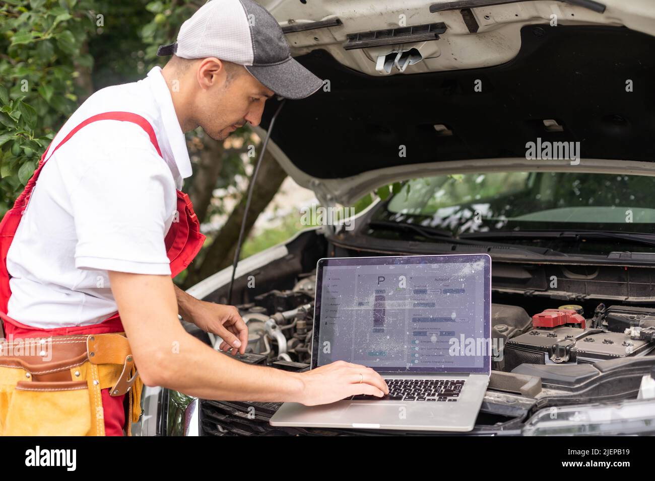 Mechanic with laptop near car engine. Modern car diagnostic program on ...