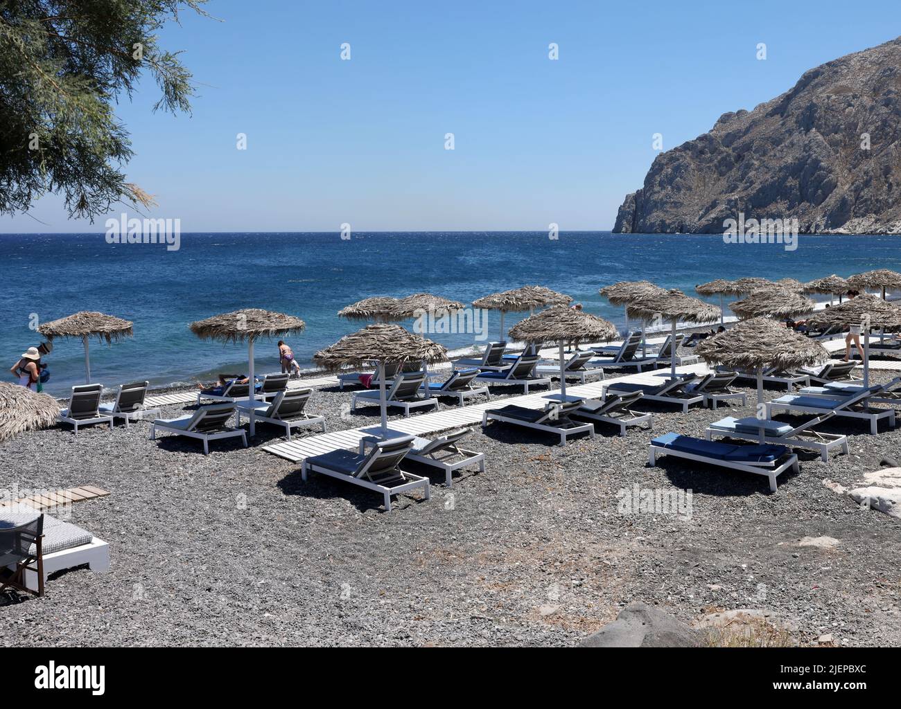 Kamari, Santorini, Greece - June 30, 2021: Sun loungers on the black ...