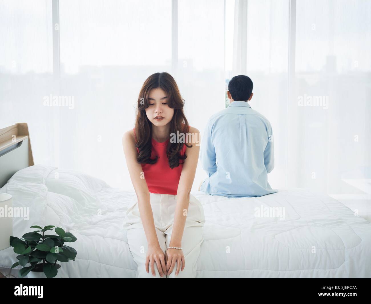 The anxiety of Asian couple lovers on the bed. Sad young woman and man ...
