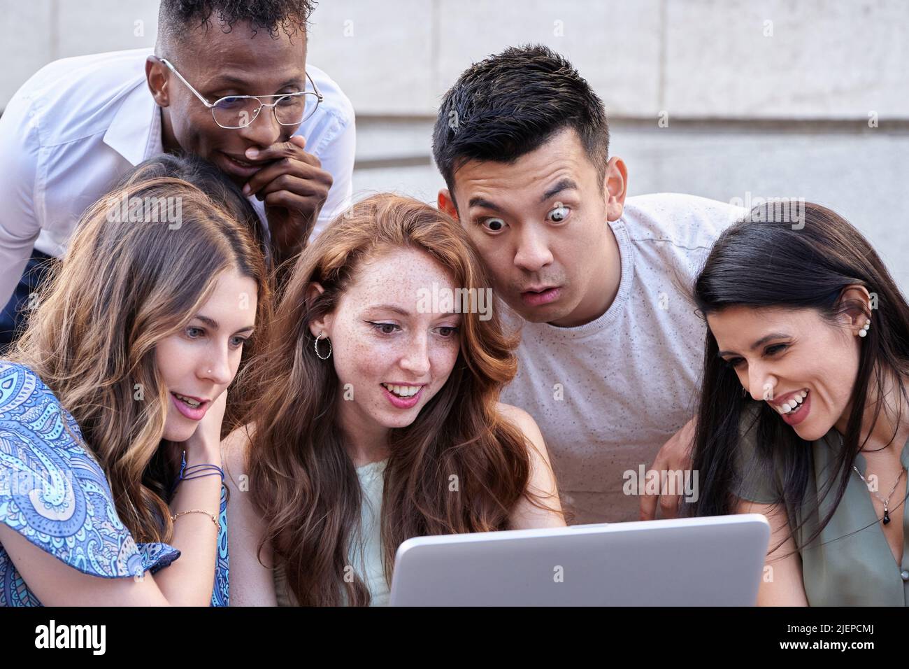 Group of multiracial people using a laptop computer together while ...
