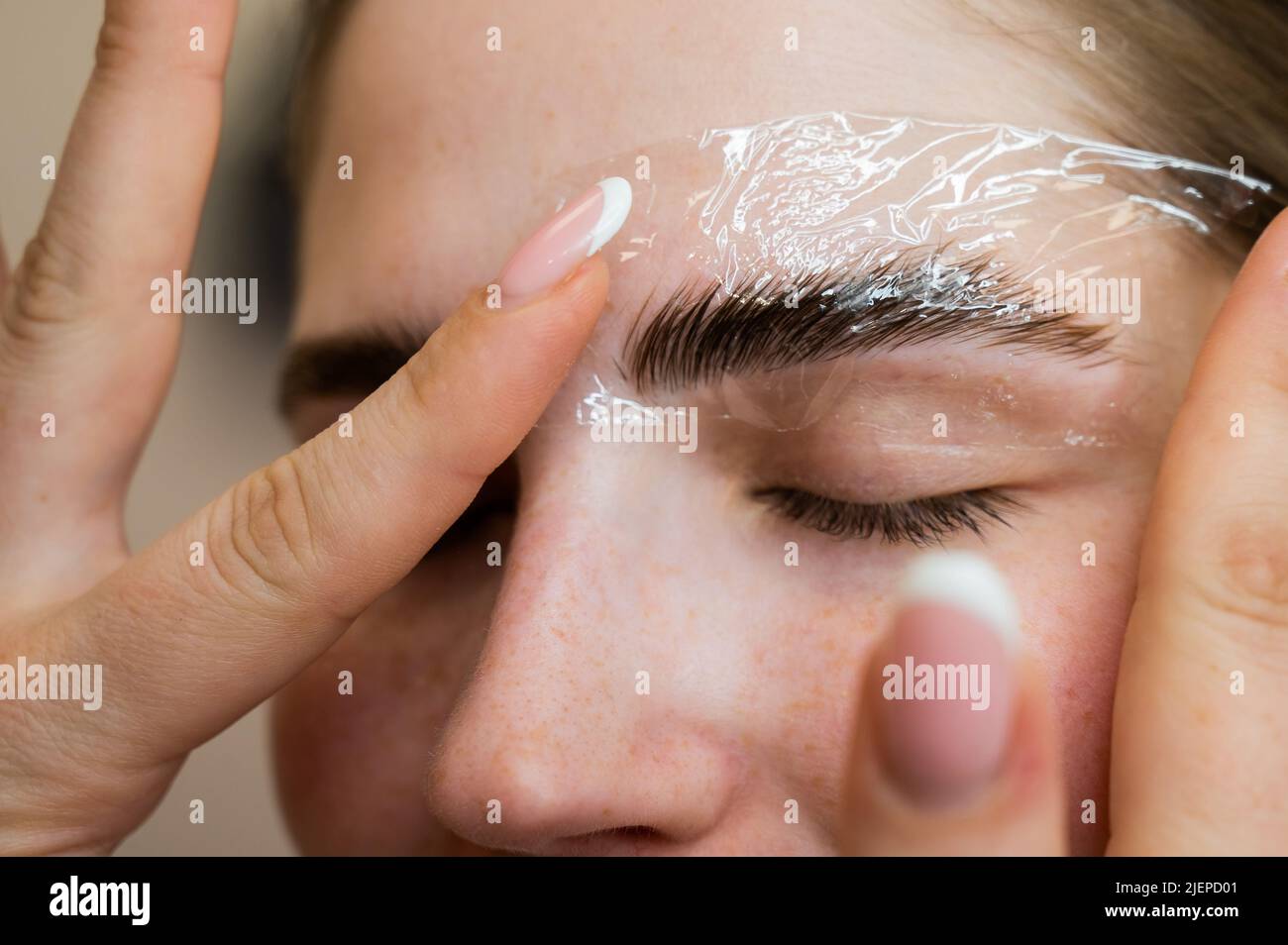 The master uses a plastic film during lamination of the eyebrows Stock ...